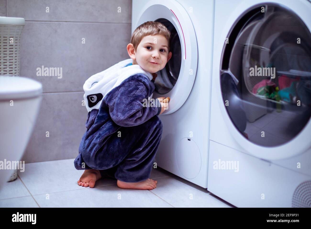 the toddler is looking into the washing machine while wash Stock Photo ...