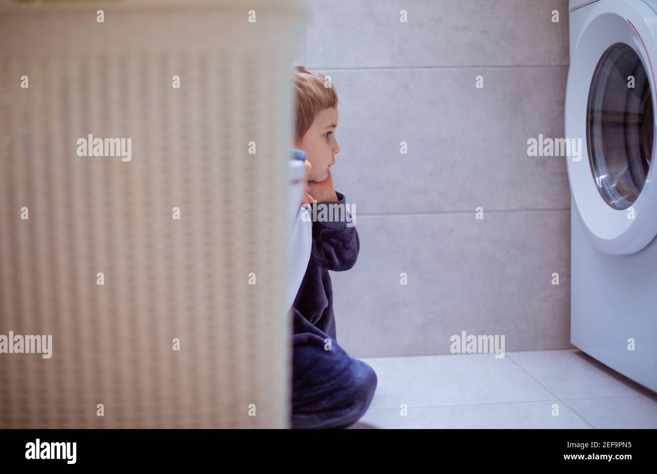 the toddler is looking into the washing machine while wash Stock Photo ...