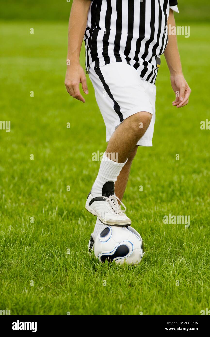 Low section view of a soccer player resting his foot on a soccer ball ...