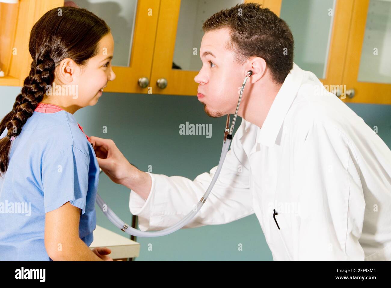Male doctor examining a girl with a stethoscope Stock Photo - Alamy