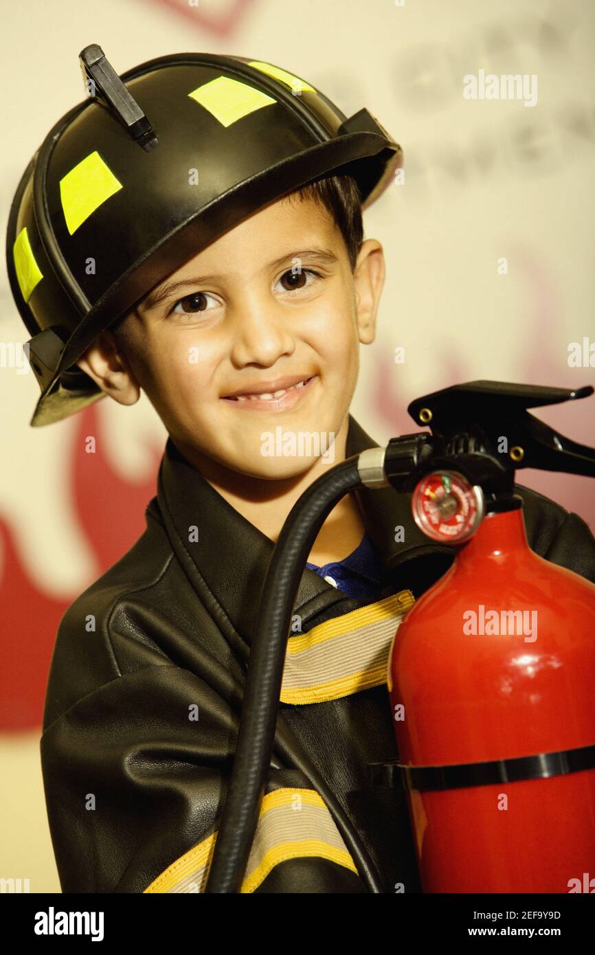 Portrait of a boy dressed as a firefighter and holding a fire ...