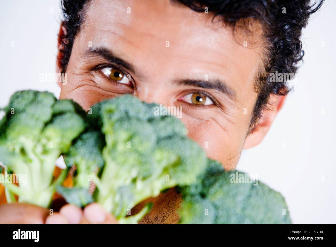 Portrait of a young man holding broccoli in front of his face Stock ...
