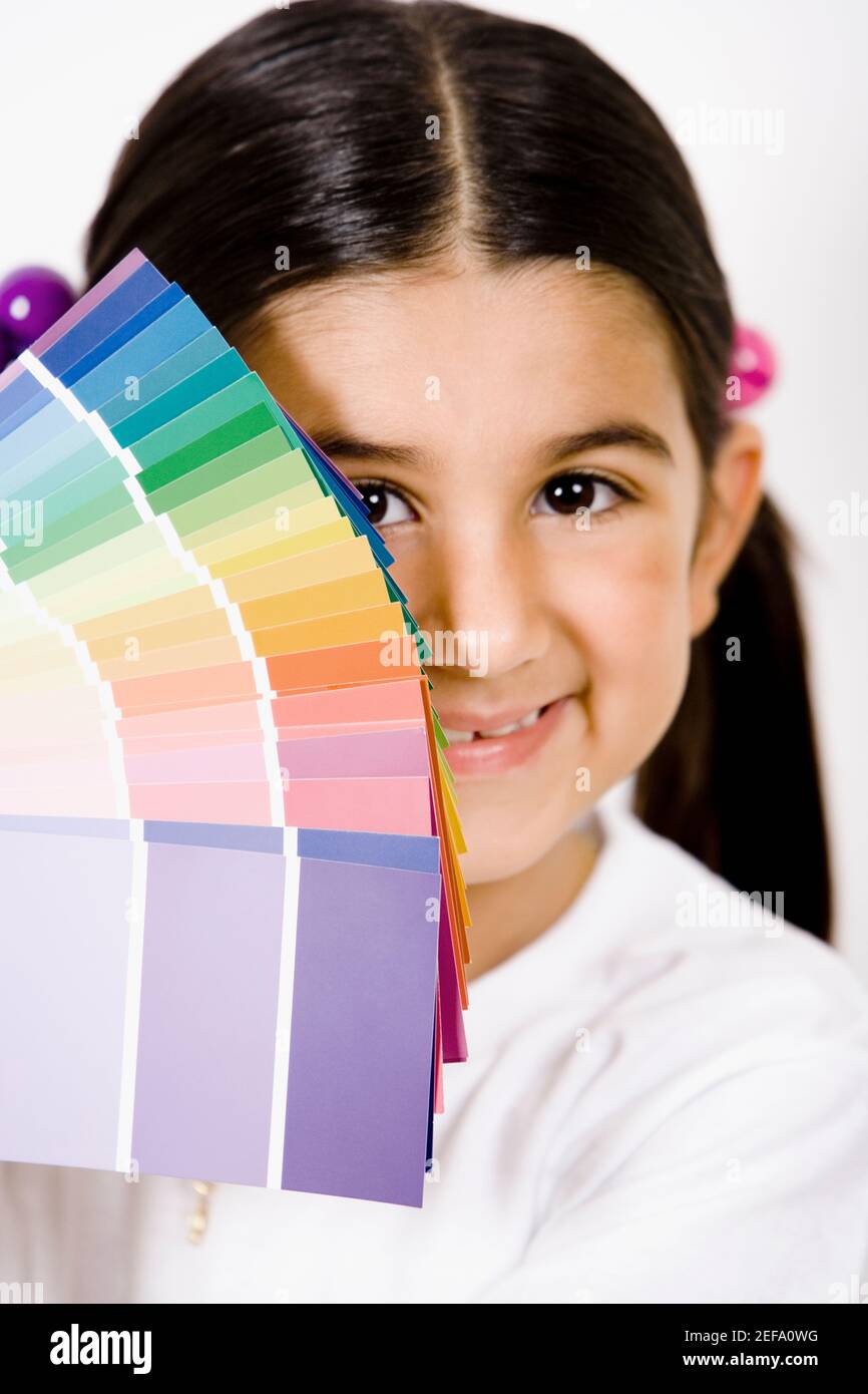 Portrait of a girl with color swatches in front of her face and smiling ...