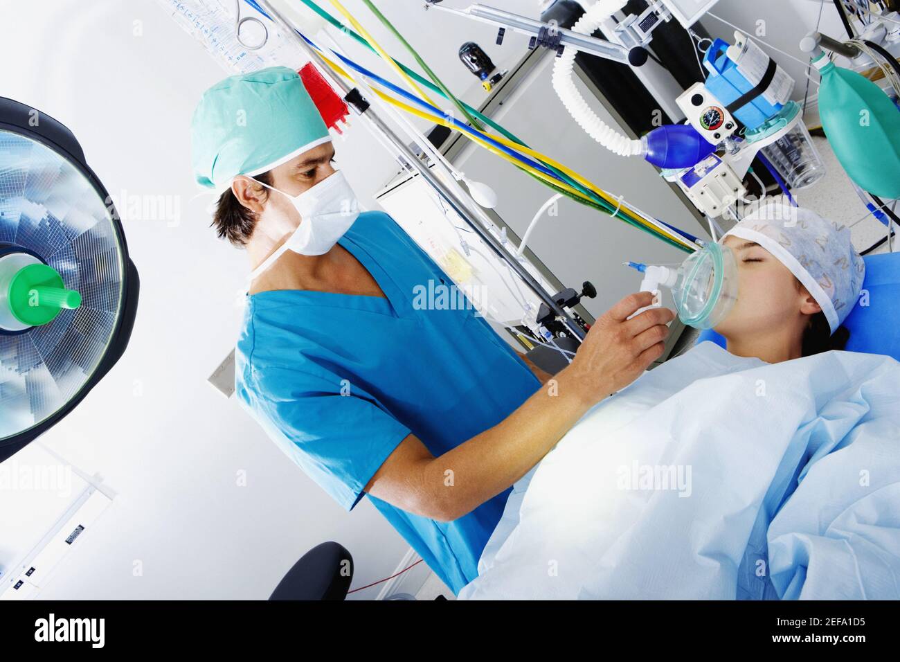 Male surgeon putting an oxygen mask on the mouth of a female patient ...