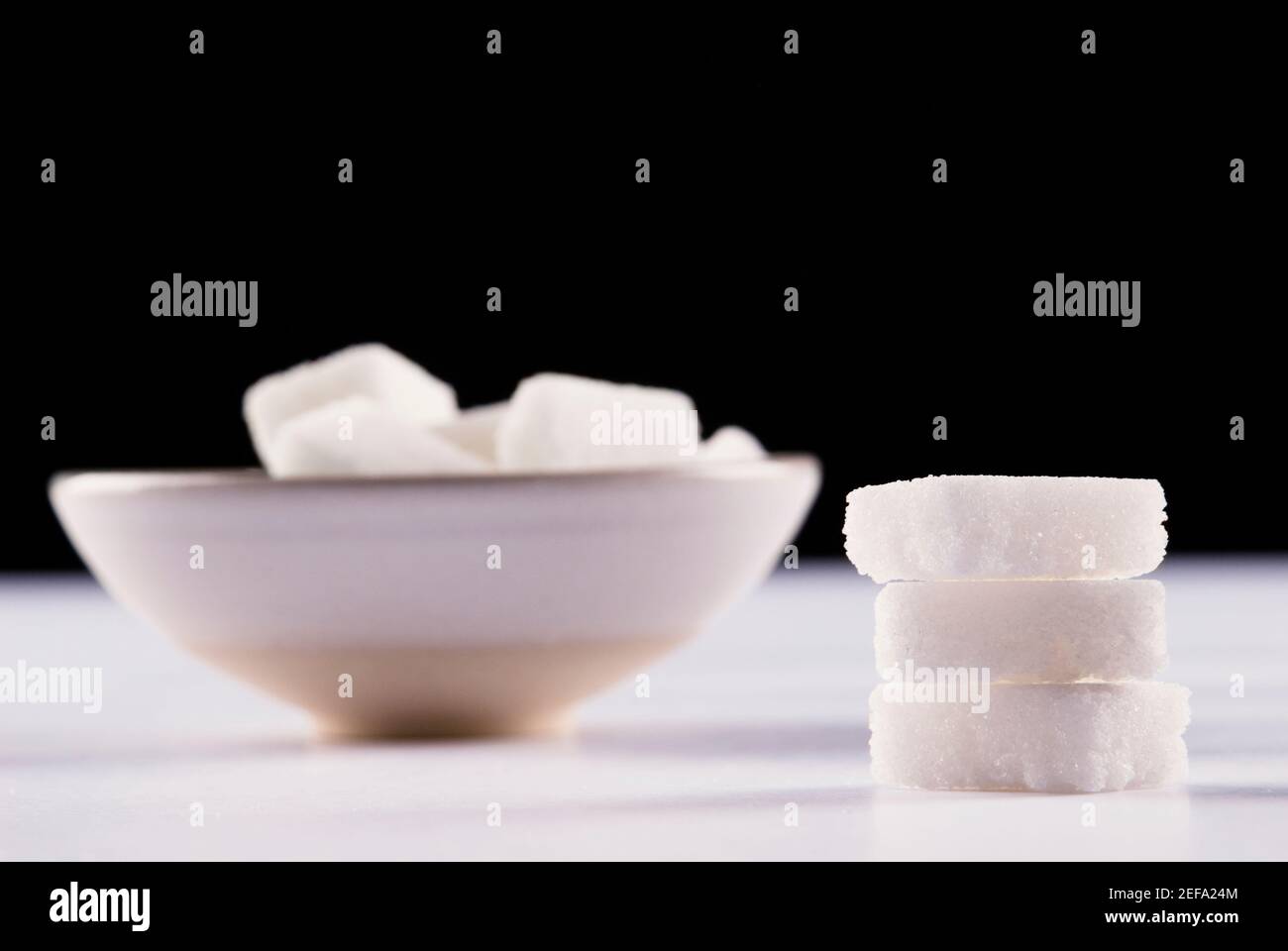 Stack of sugar cubes and a bowl of sugar cubes in the background Stock ...