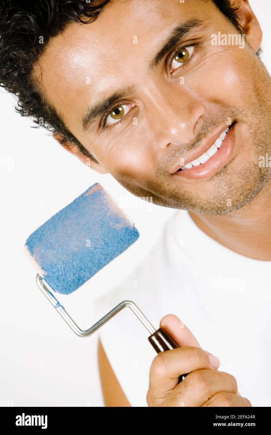 Portrait of a young man holding a paint roller and smiling Stock Photo ...
