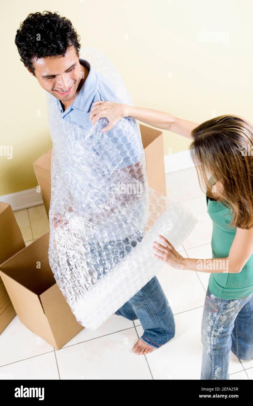 High angle view of a mid adult woman wrapping a bubble wrap around a ...
