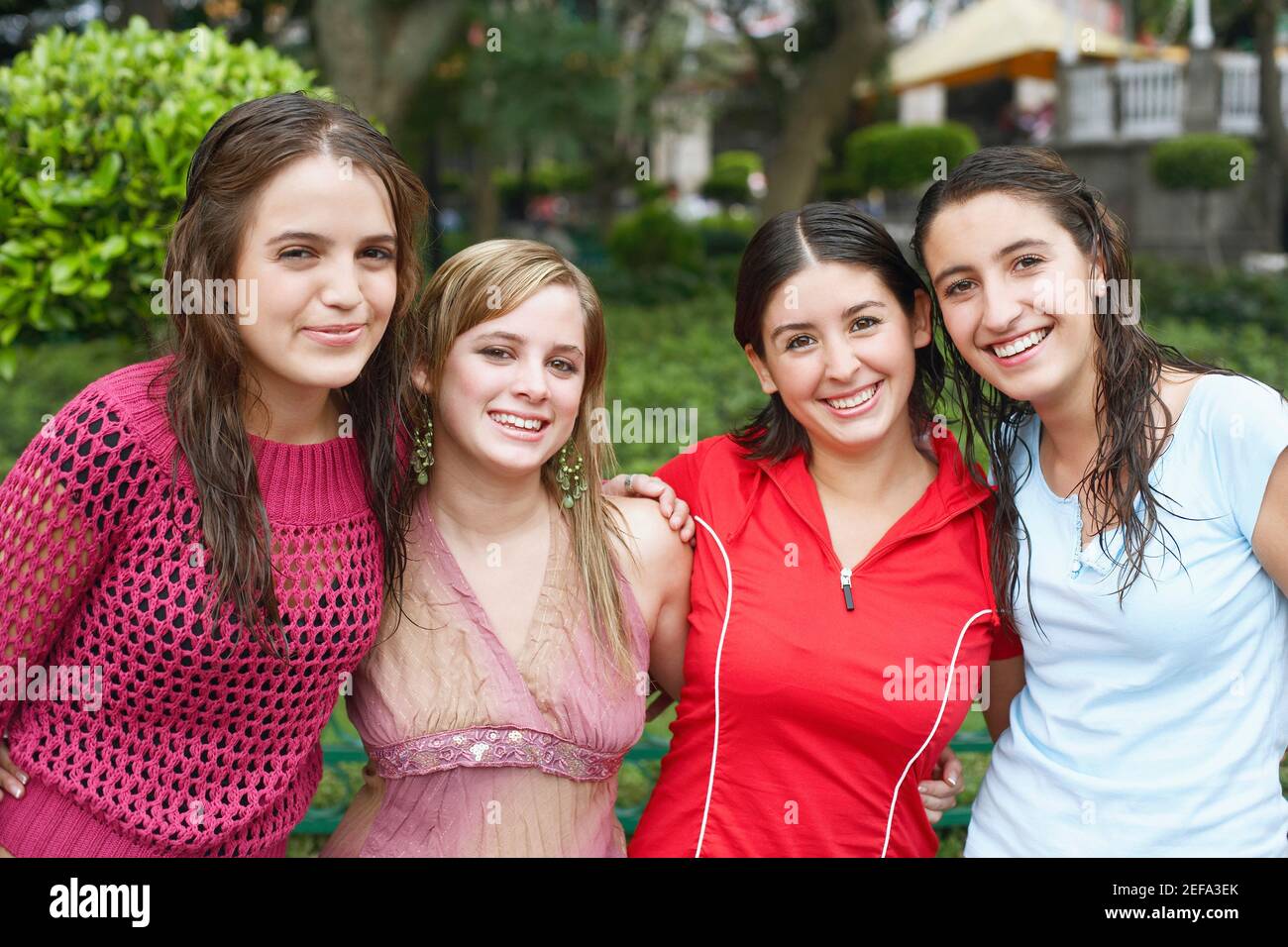 Portrait of four young women standing together and smiling Stock Photo ...