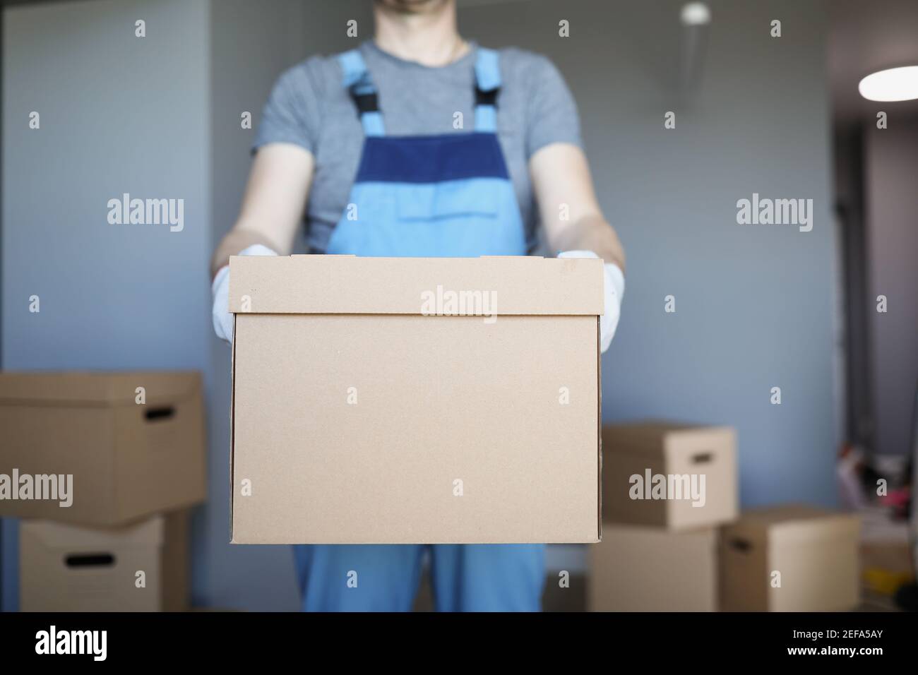 Male courier is holding large cardboard box Stock Photo - Alamy