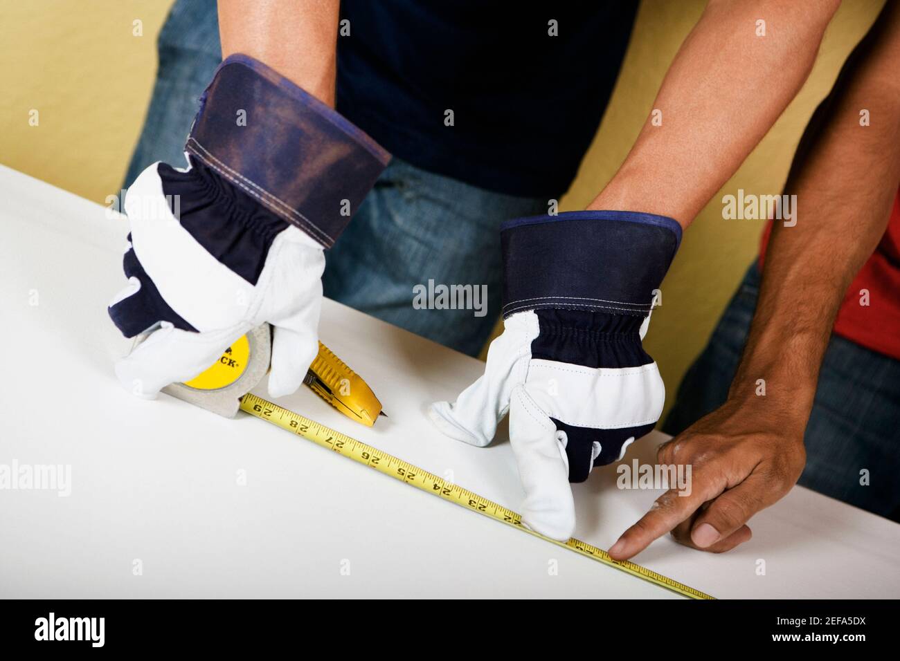 Mid section view of two men measuring with a measuring tape Stock Photo ...