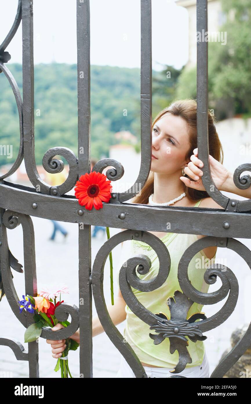 Young woman standing behind a gate Stock Photo - Alamy
