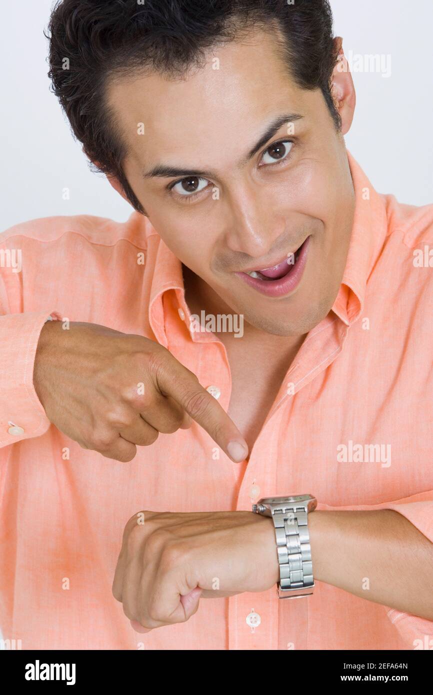 Portrait of a young man pointing at his wristwatch Stock Photo - Alamy