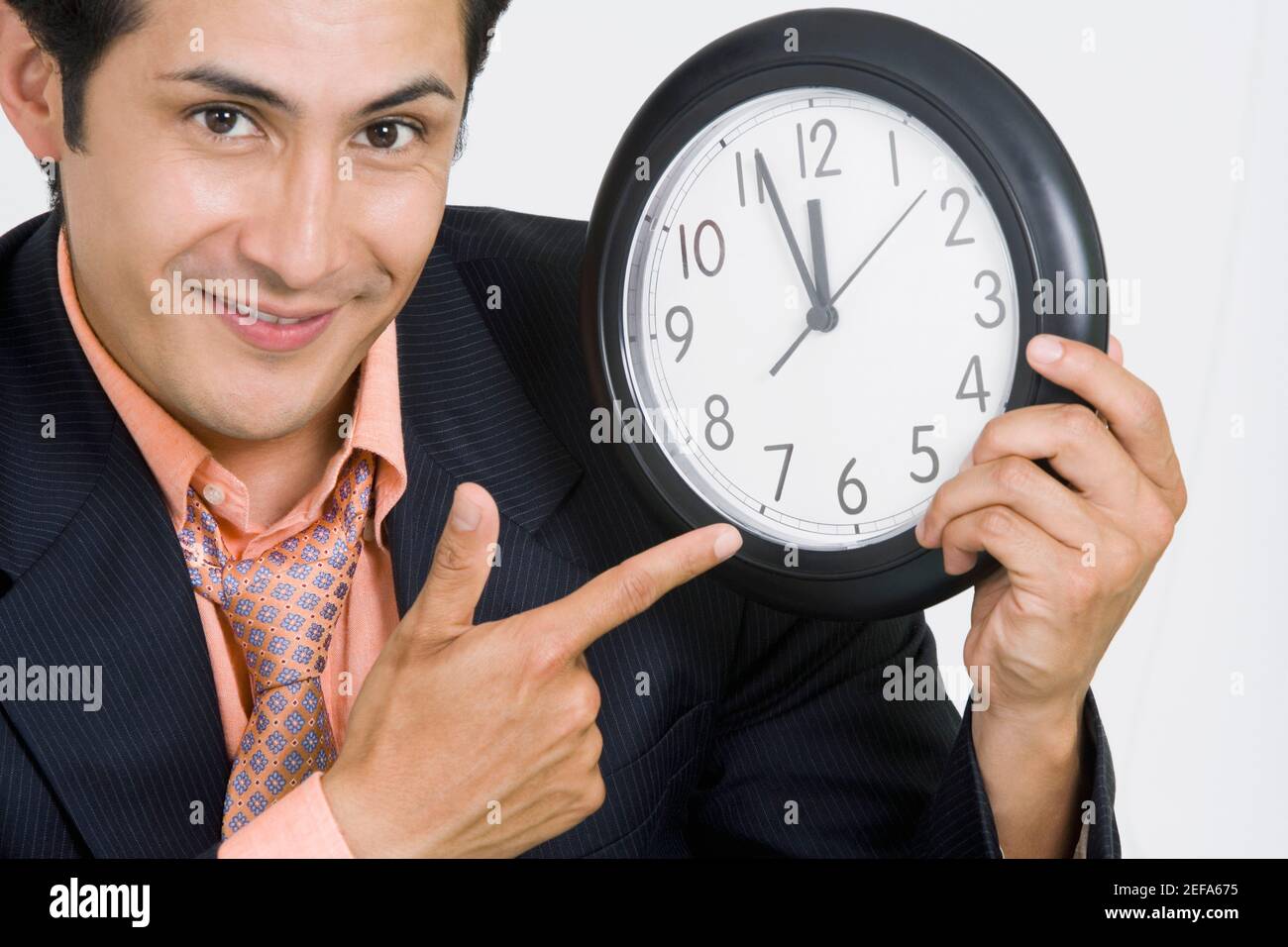 Portrait of a businessman pointing at a clock Stock Photo - Alamy