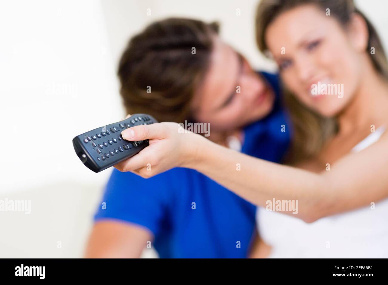Young woman holding a remote control with a young man kissing her Stock ...