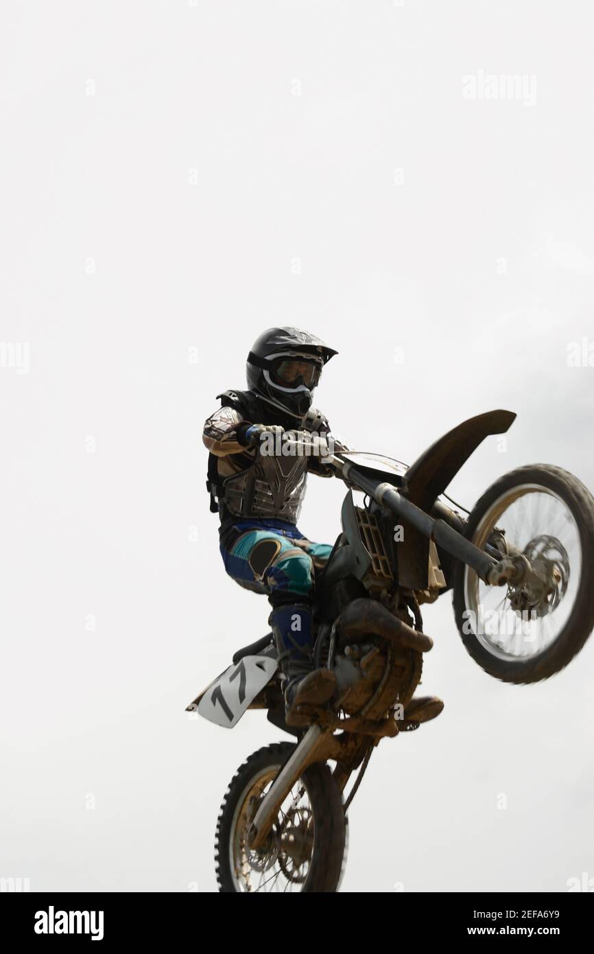 Low angle view of a motocross rider performing a jump on a motorcycle ...
