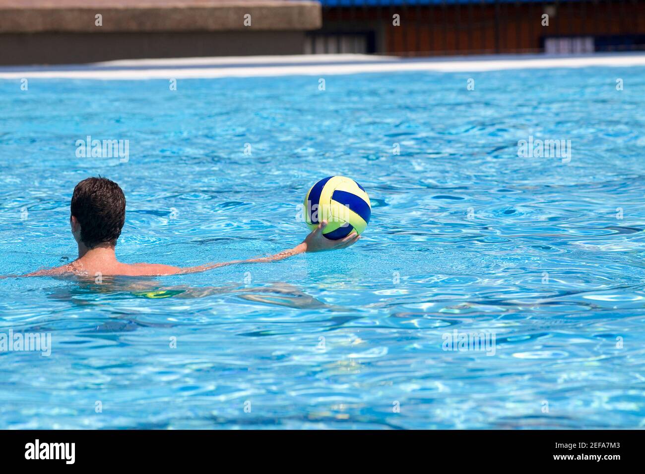 Rear view of a man playing water polo in a swimming pool Stock Photo ...