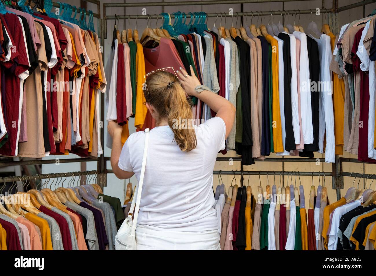 woman chooses clothes going through the broadcaster in the store at the ...
