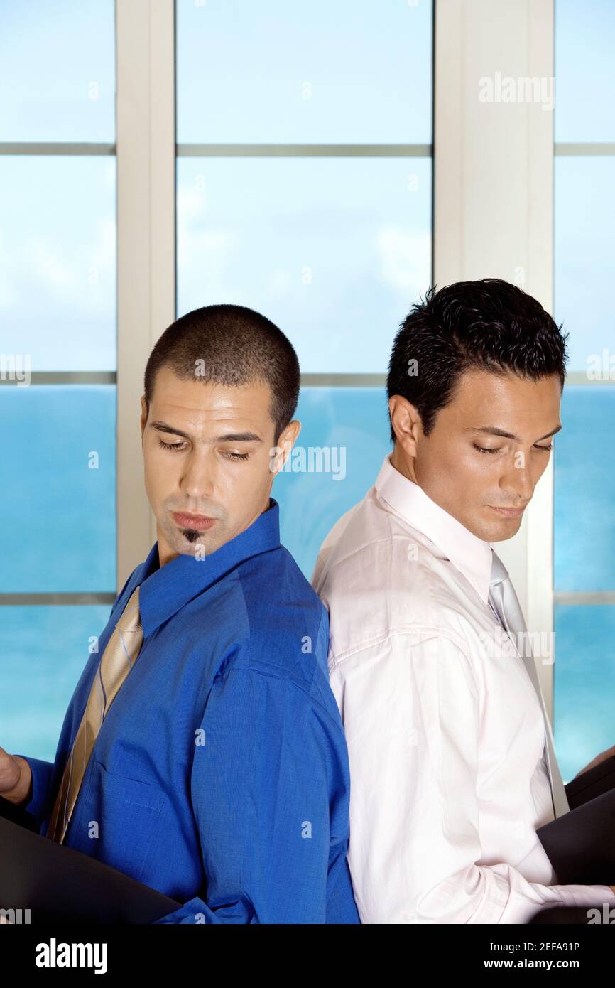 Side profile of two businessmen standing back to back Stock Photo - Alamy