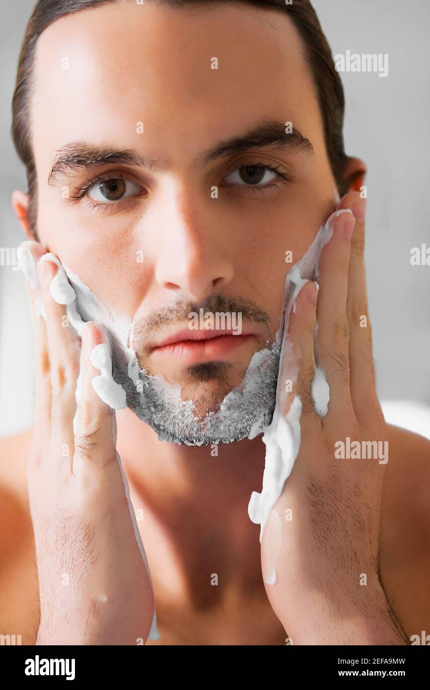 Portrait of a young man applying shaving cream on his face Stock Photo - Alamy
