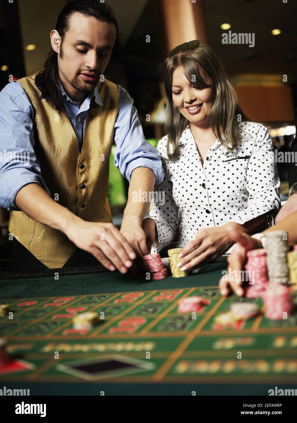 Casino worker arranging gambling chips for a young woman in a casino ...