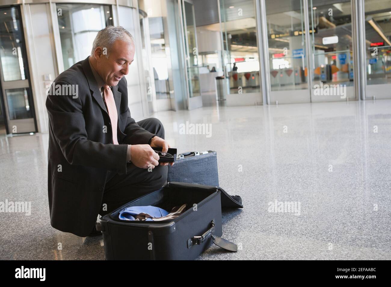 Side profile of a businessman packing his suitcase at an airport Stock ...