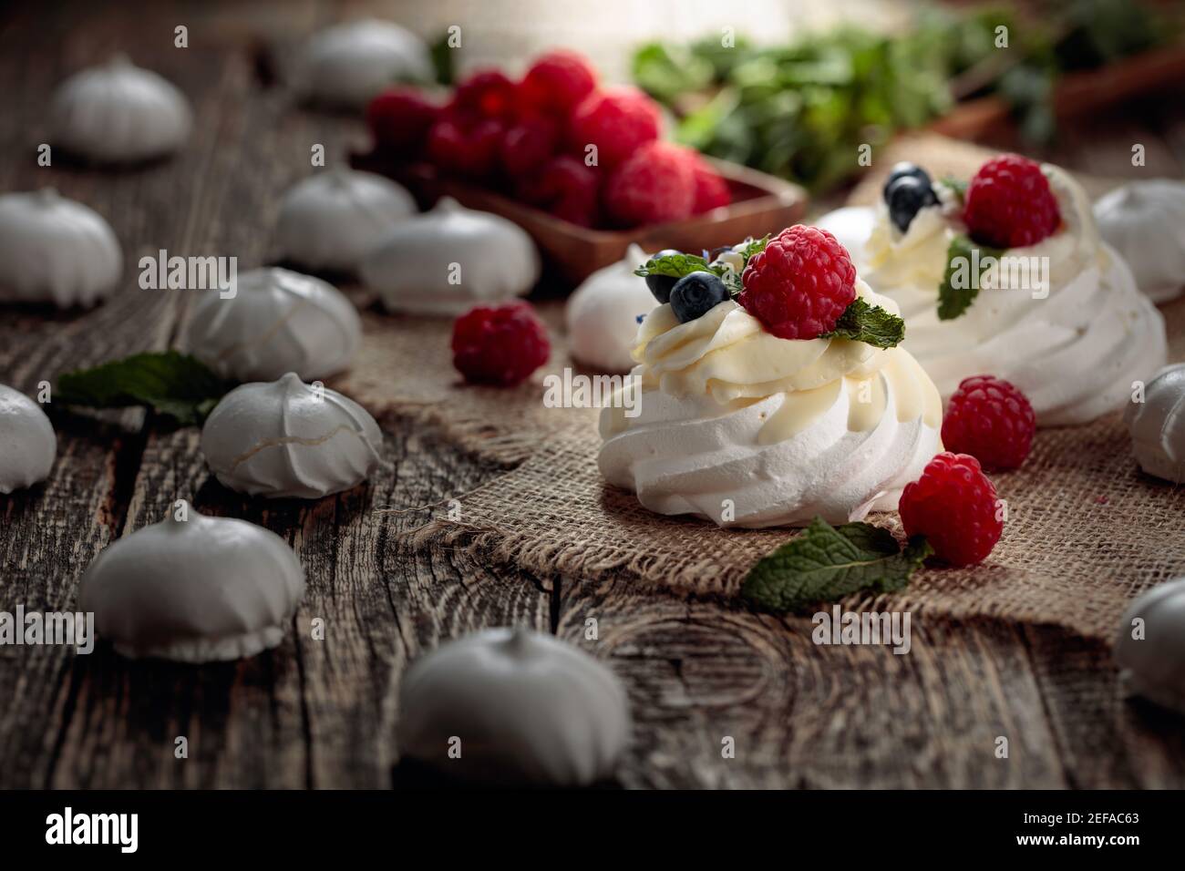 Dessert Pavlova and small meringues on a rustic background Stock Photo ...