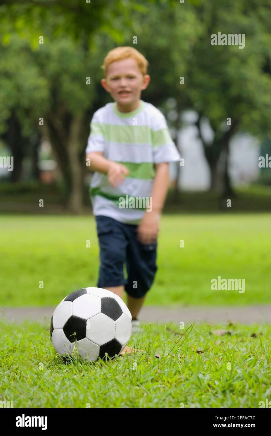 Boy playing football in a park Stock Photo - Alamy
