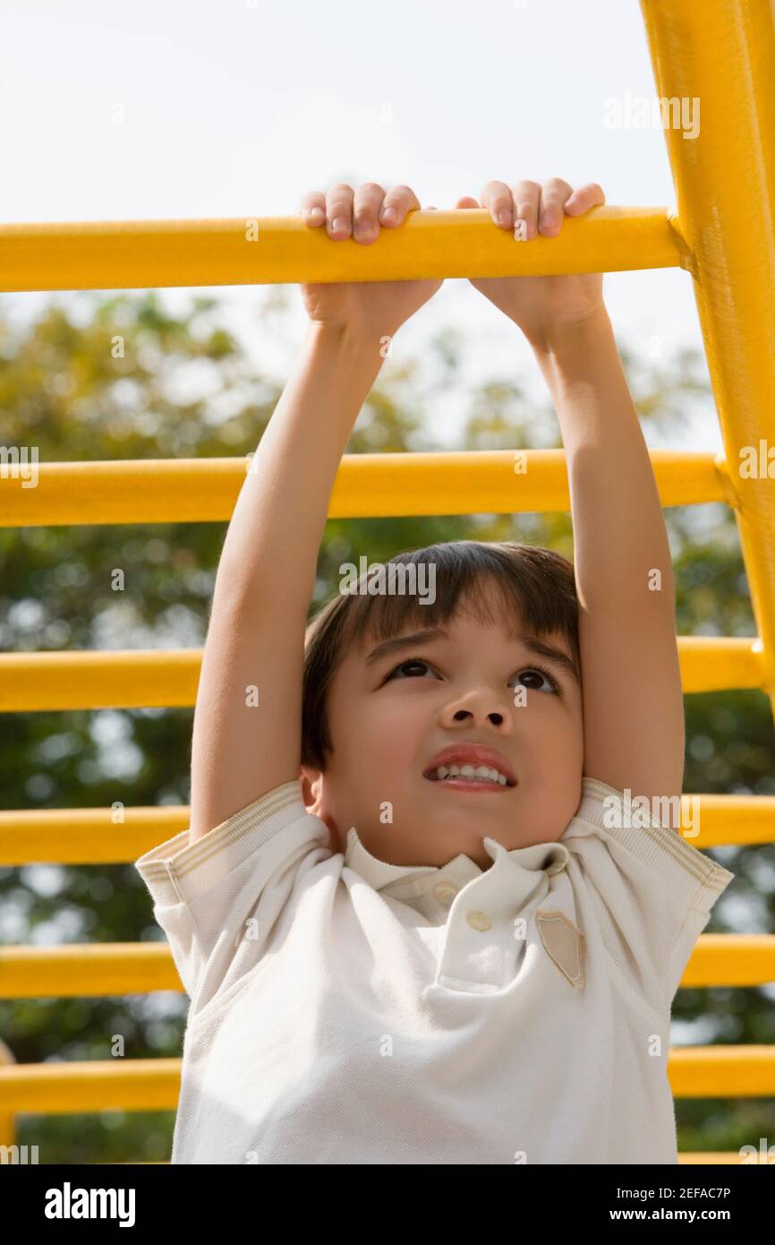 Low angle view of a boy hanging on monkey bars hi-res stock photography ...