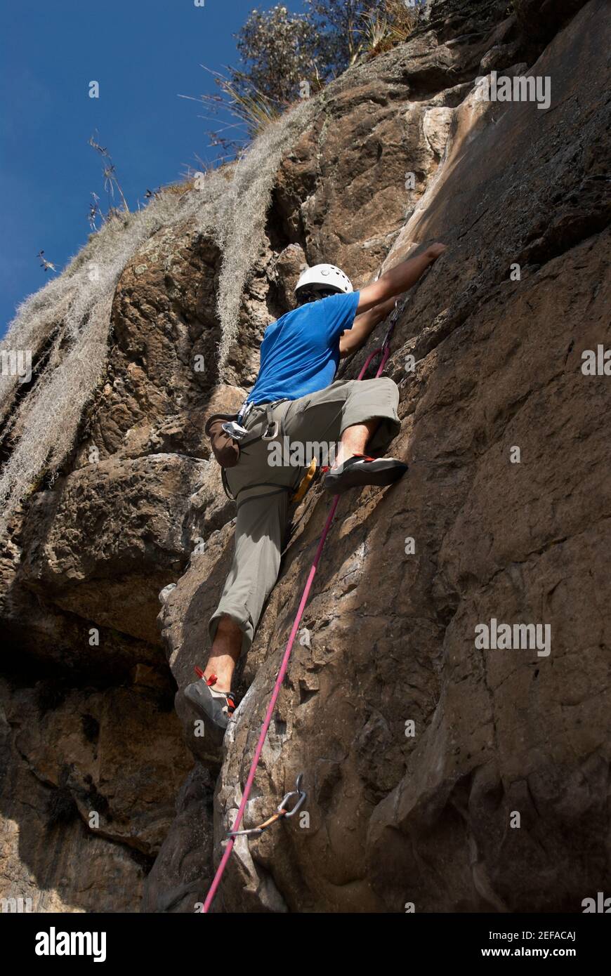 Low angle view of a male rock climber scaling a rock face Stock Photo ...