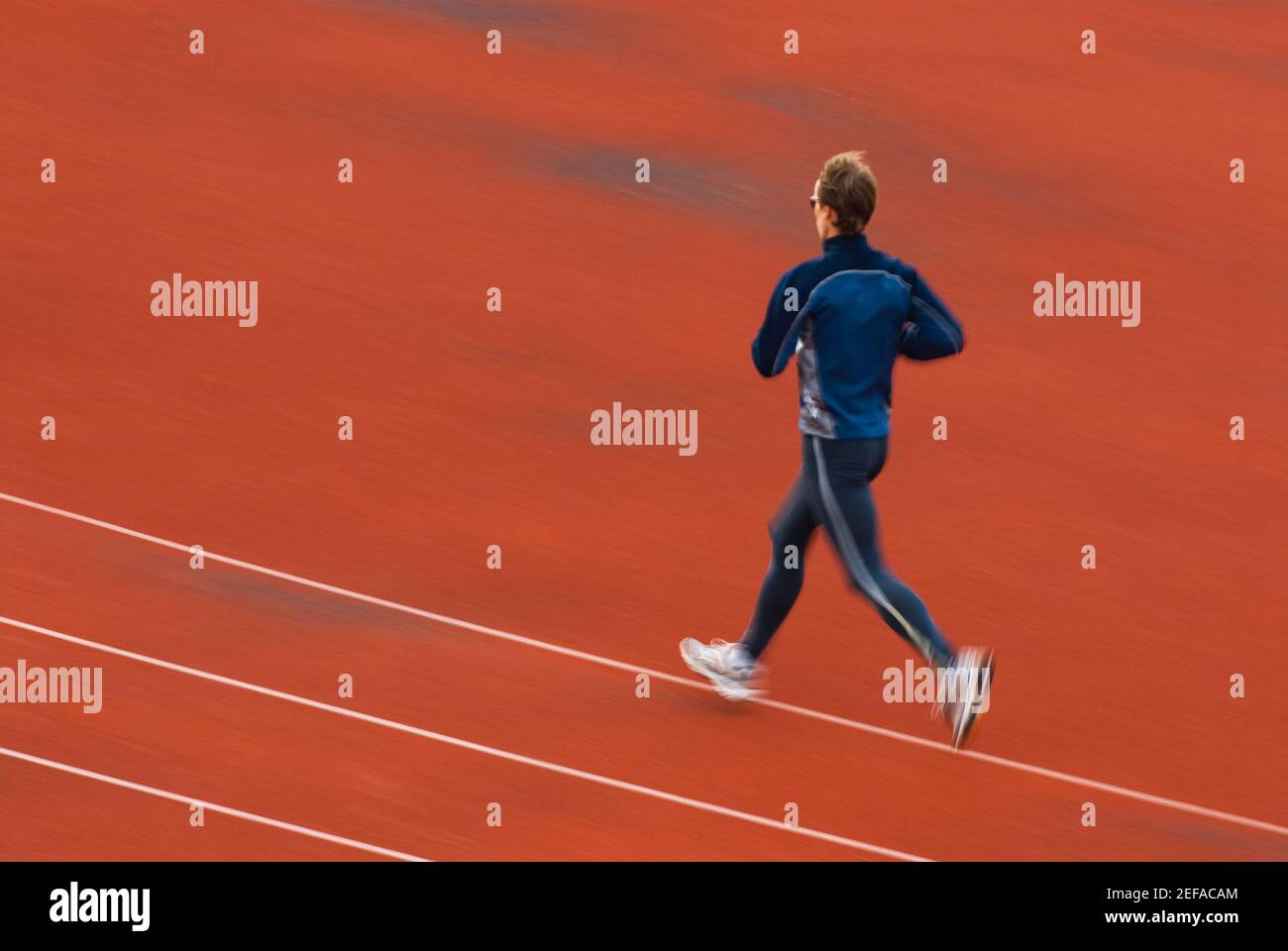 Rear view of a mid adult man running on a running track Stock Photo - Alamy