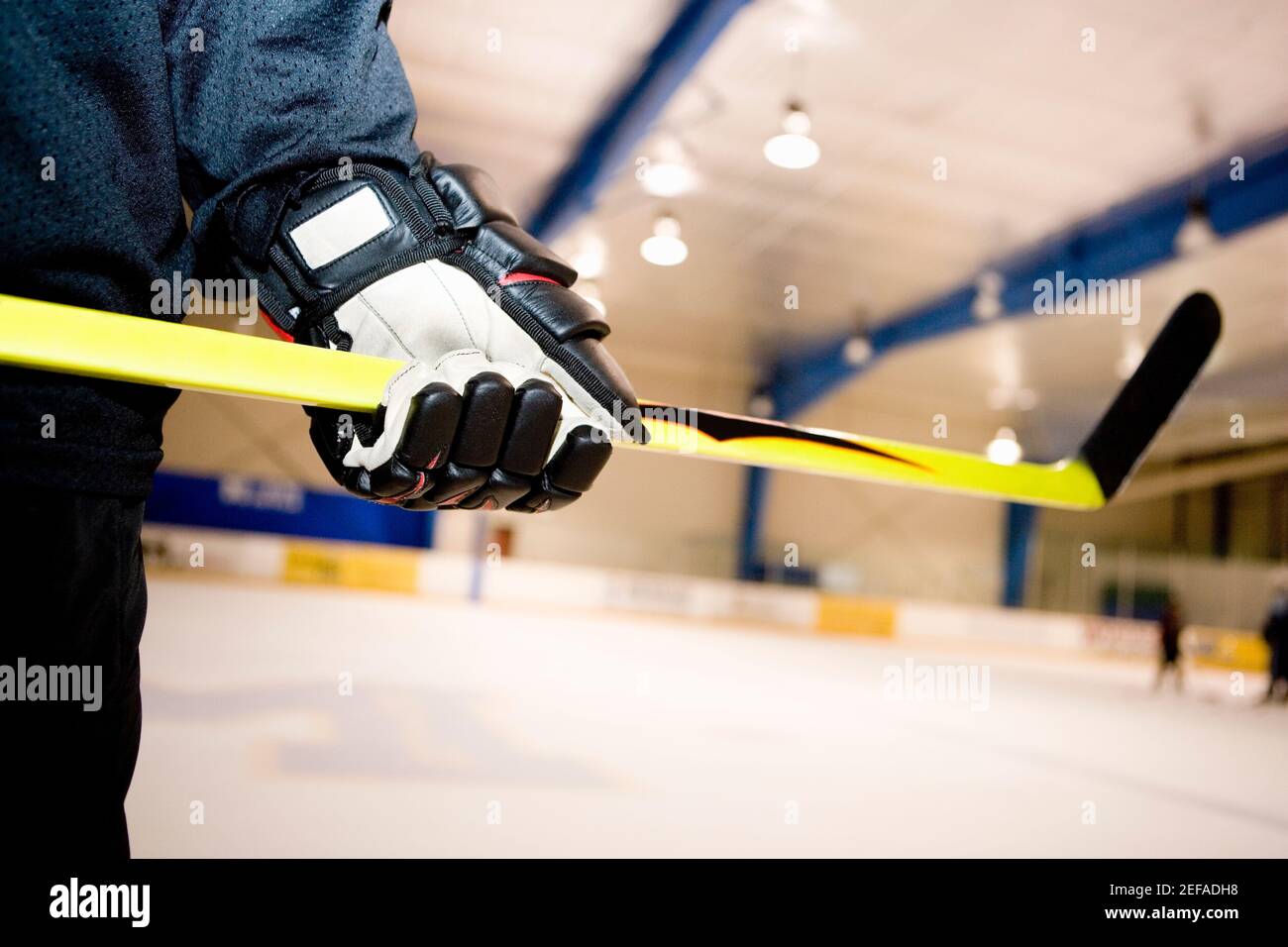 Mid section view of an ice hockey player holding an ice hockey stick ...