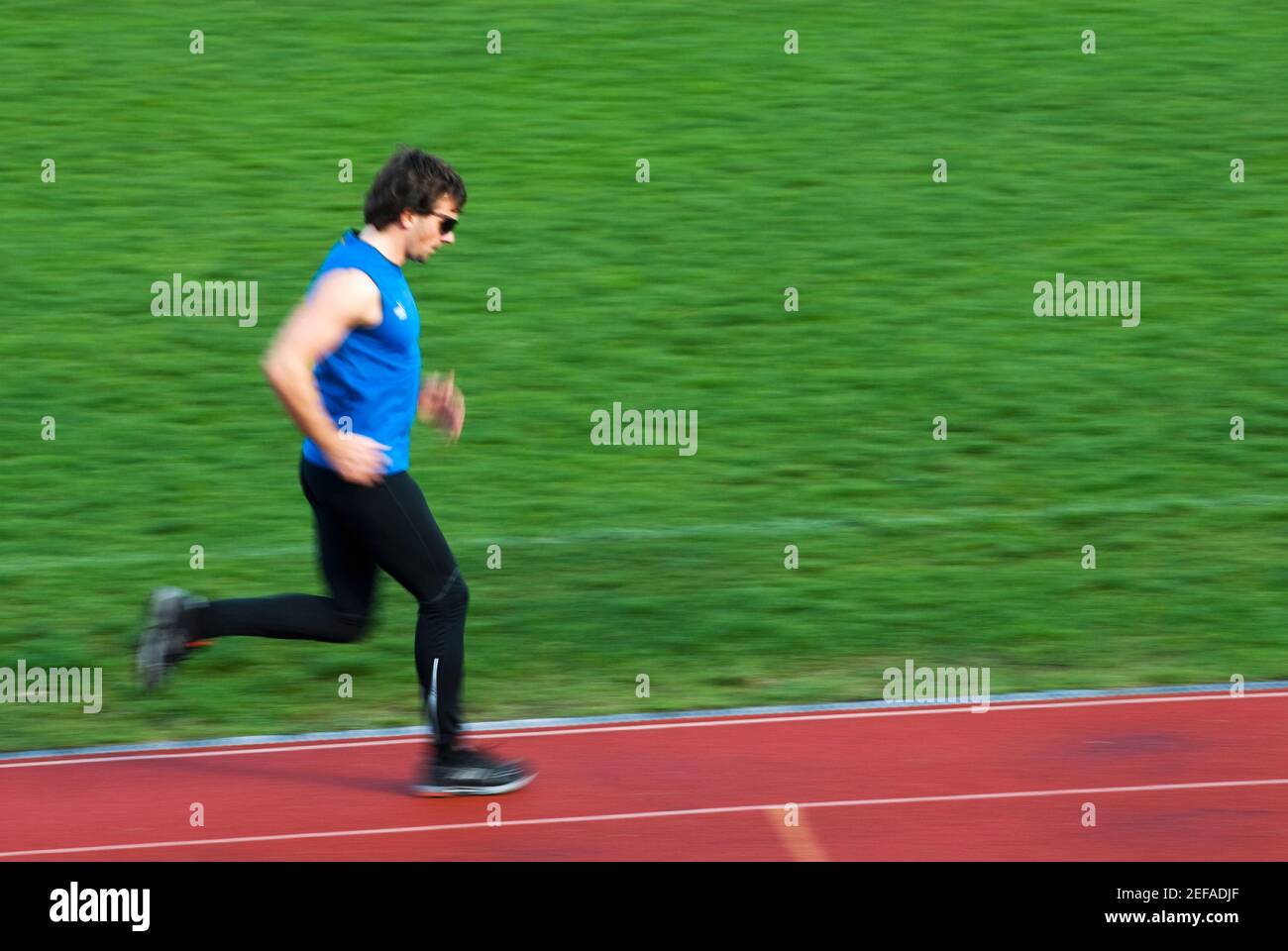 Side profile of a mid adult man running on a sports track Stock Photo ...