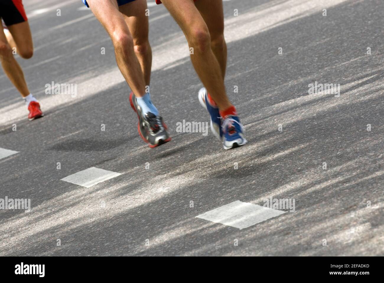 Low section view of three track runners running Stock Photo - Alamy