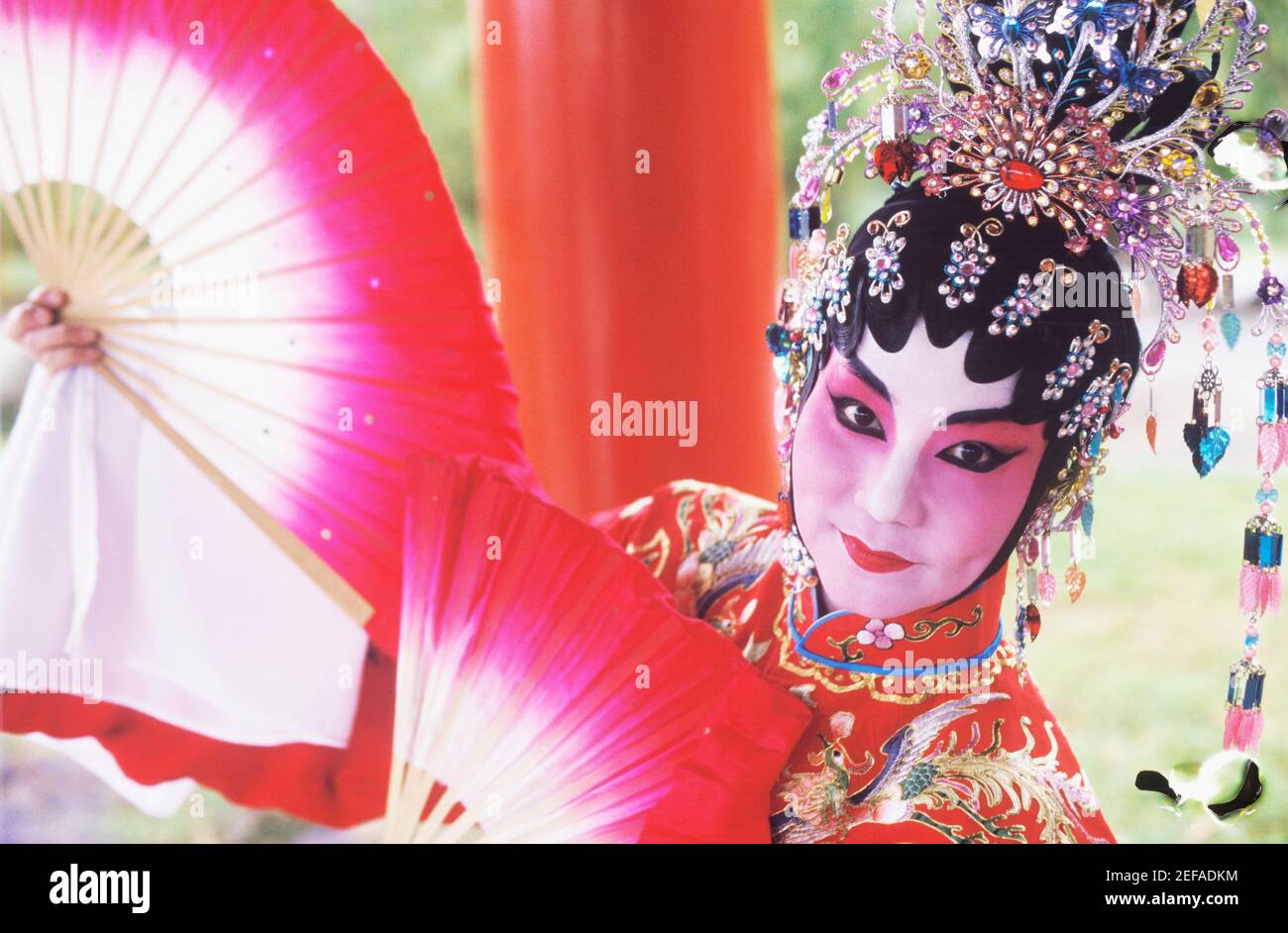 Portrait of a female Chinese opera performer holding folding fans ...