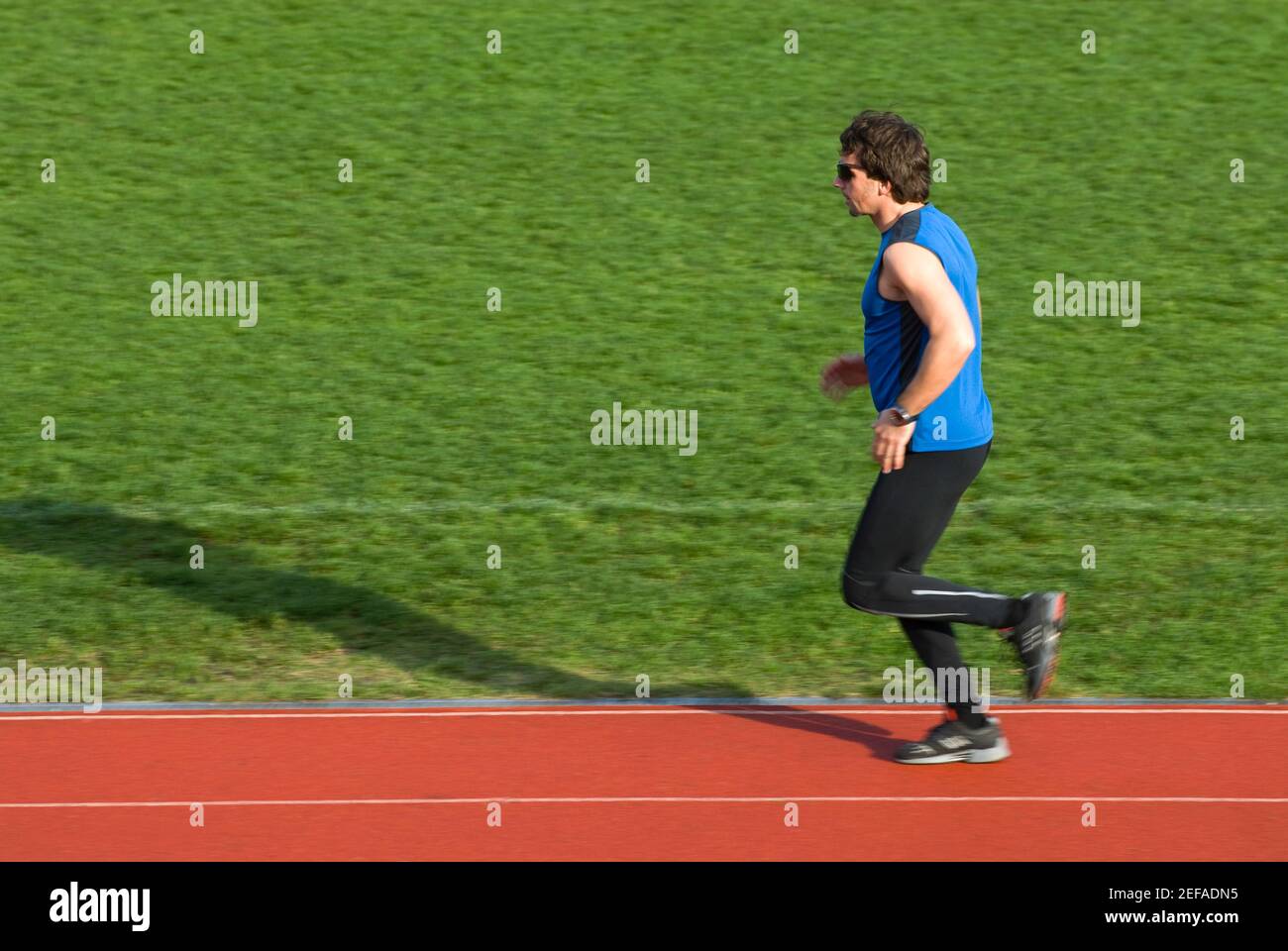Side profile of a mid adult man running on a running track Stock Photo ...