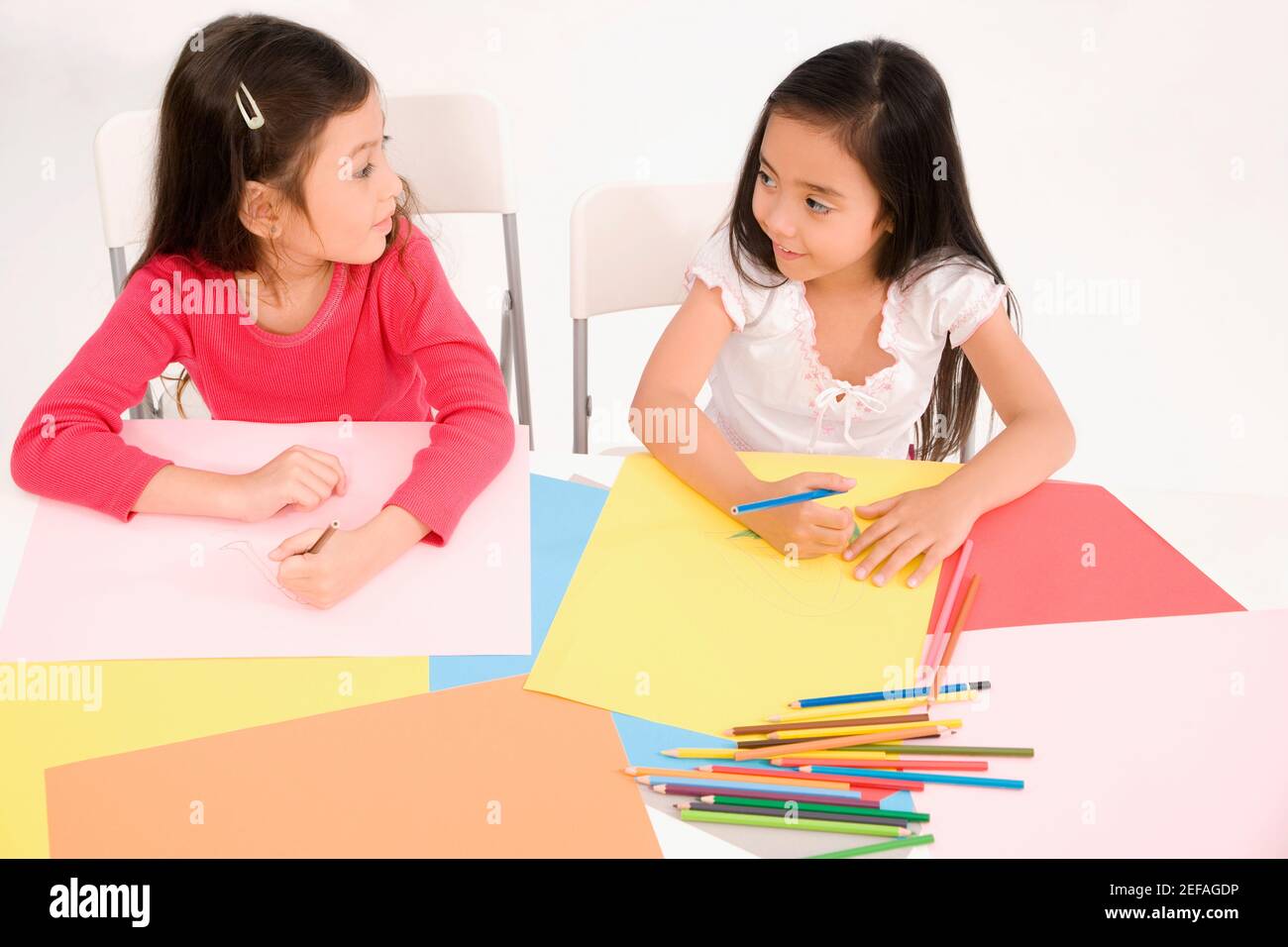 Two schoolgirls drawing in an art class and looking at each other Stock ...
