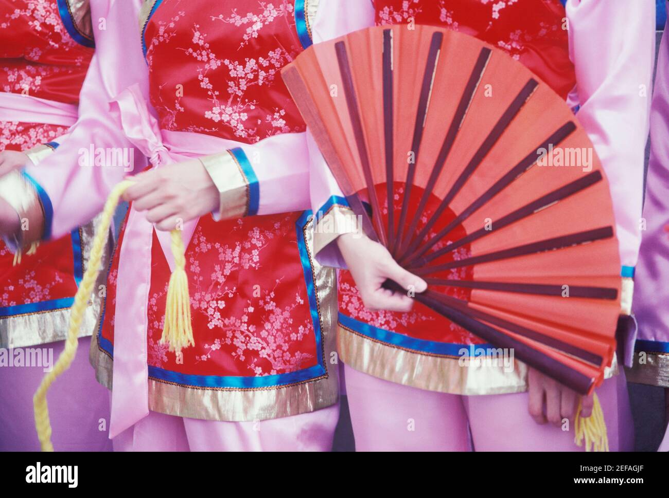 Mid section view of three women holding a folding fan and a rope Stock ...