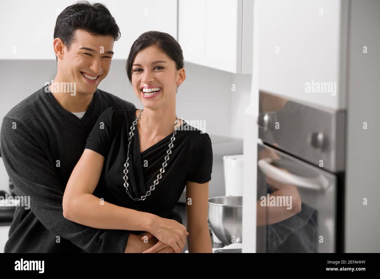 Young couple smiling in the kitchen Stock Photo - Alamy