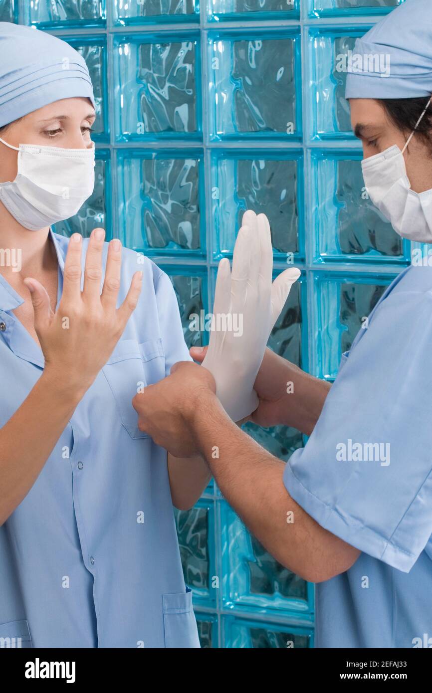 Male surgeon adjusting a surgical glove of a female surgeon Stock Photo ...