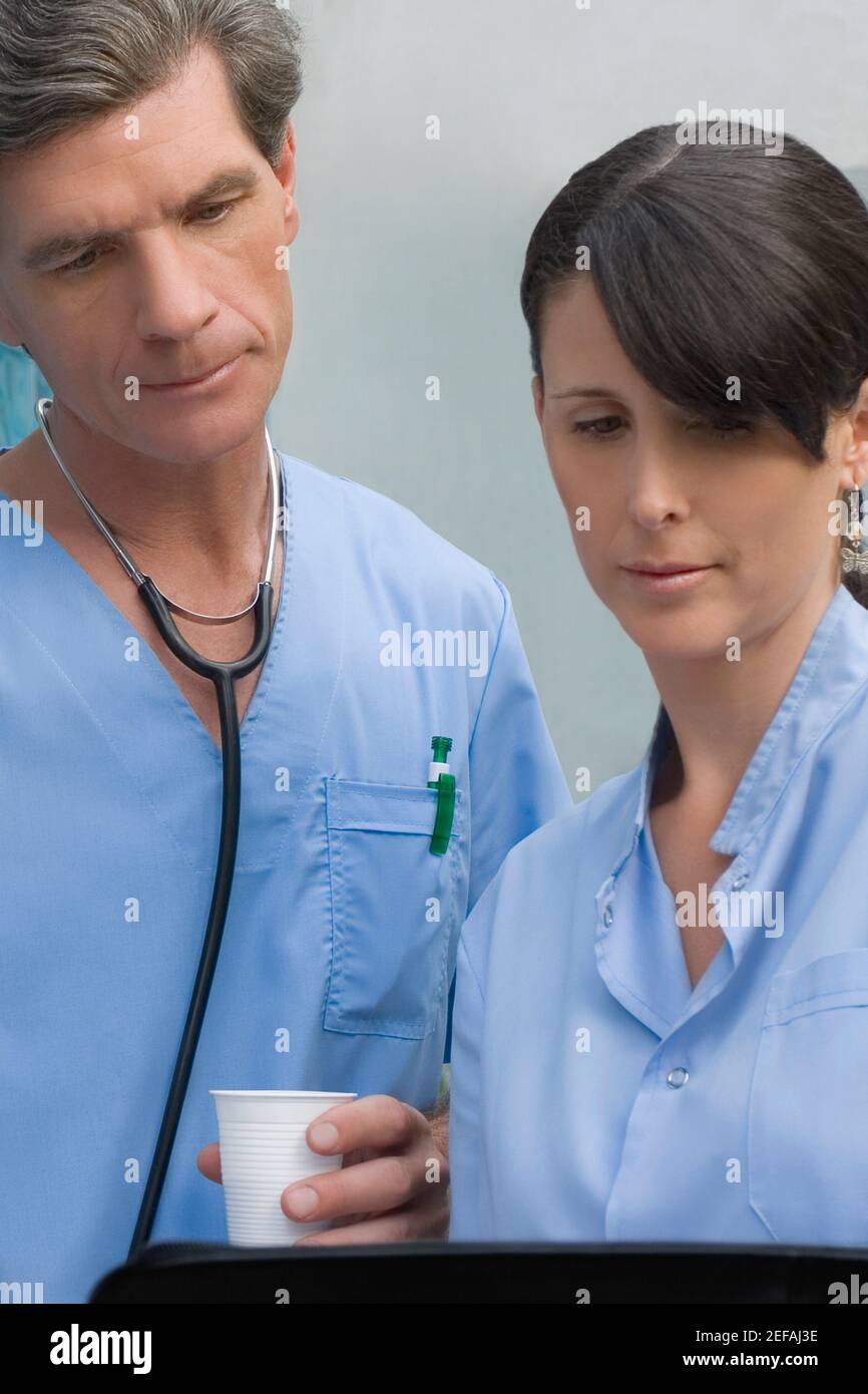 Male surgeon and a female surgeon looking at a medical record Stock ...