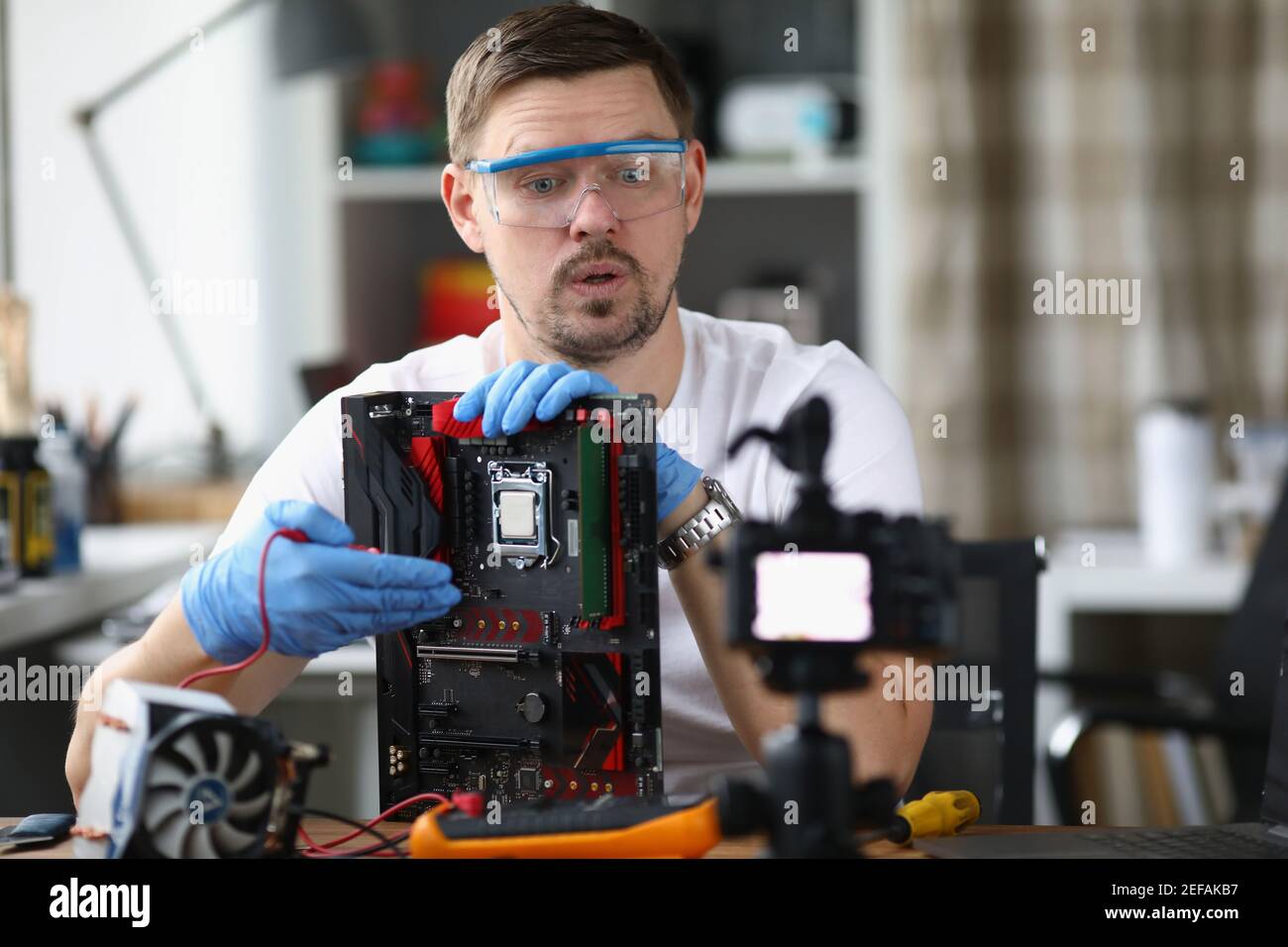 Gloved craftsman holds disassembled computer equipment and shows it to ...