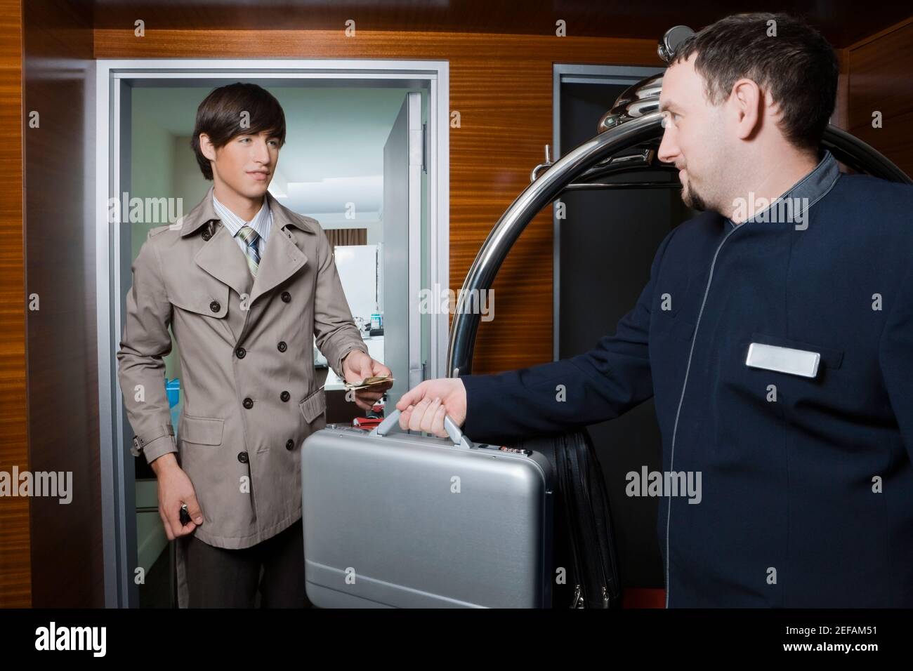 Room service man handing over a briefcase to a businessman Stock Photo ...