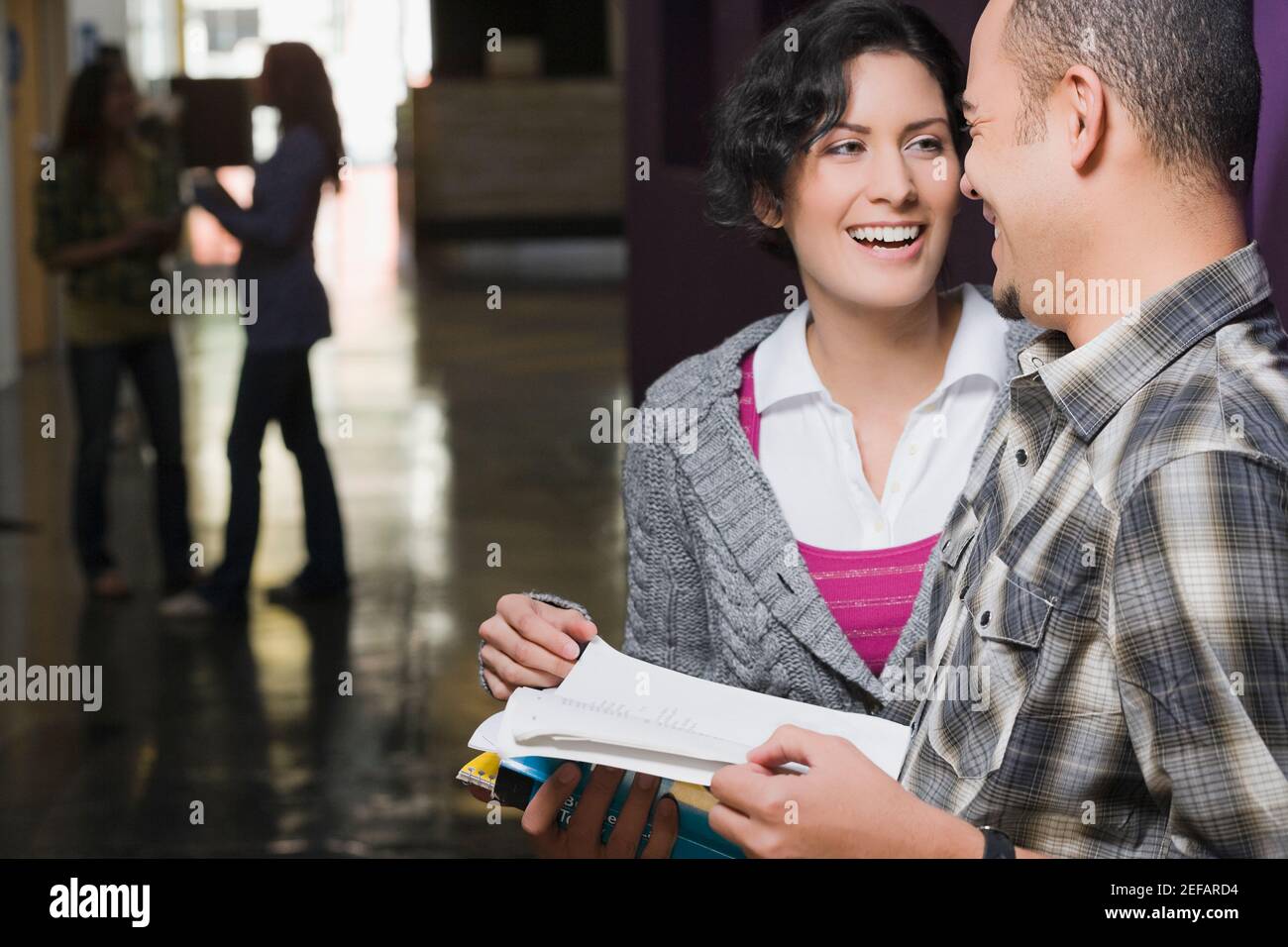 Two university students talking in a corridor Stock Photo - Alamy