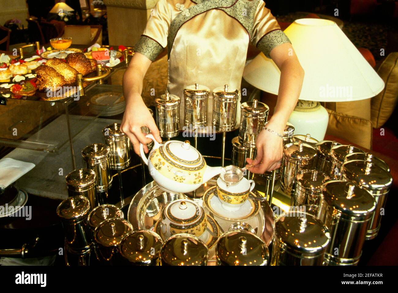 Mid section view of a waitress pouring tea in tea cups, Pudong Shangri ...