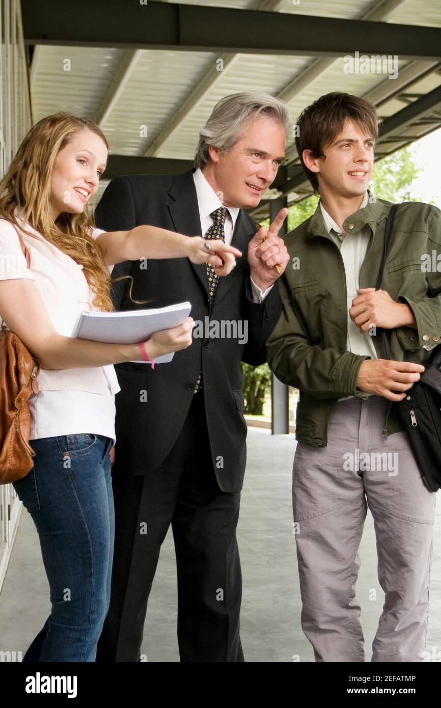 Male professor pointing with two university students standing beside ...