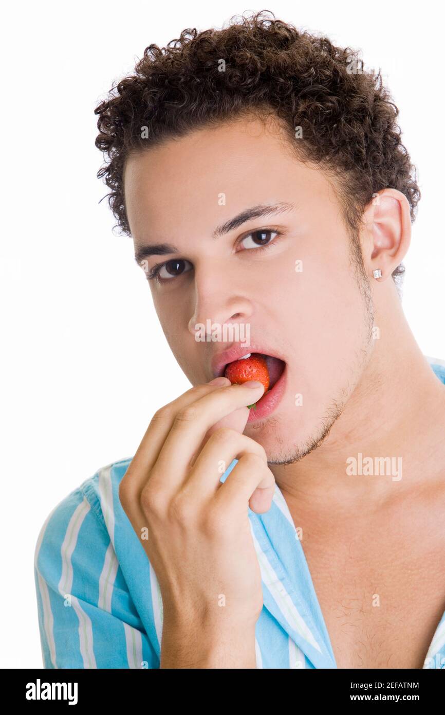 Portrait of a young man eating a strawberry Stock Photo - Alamy