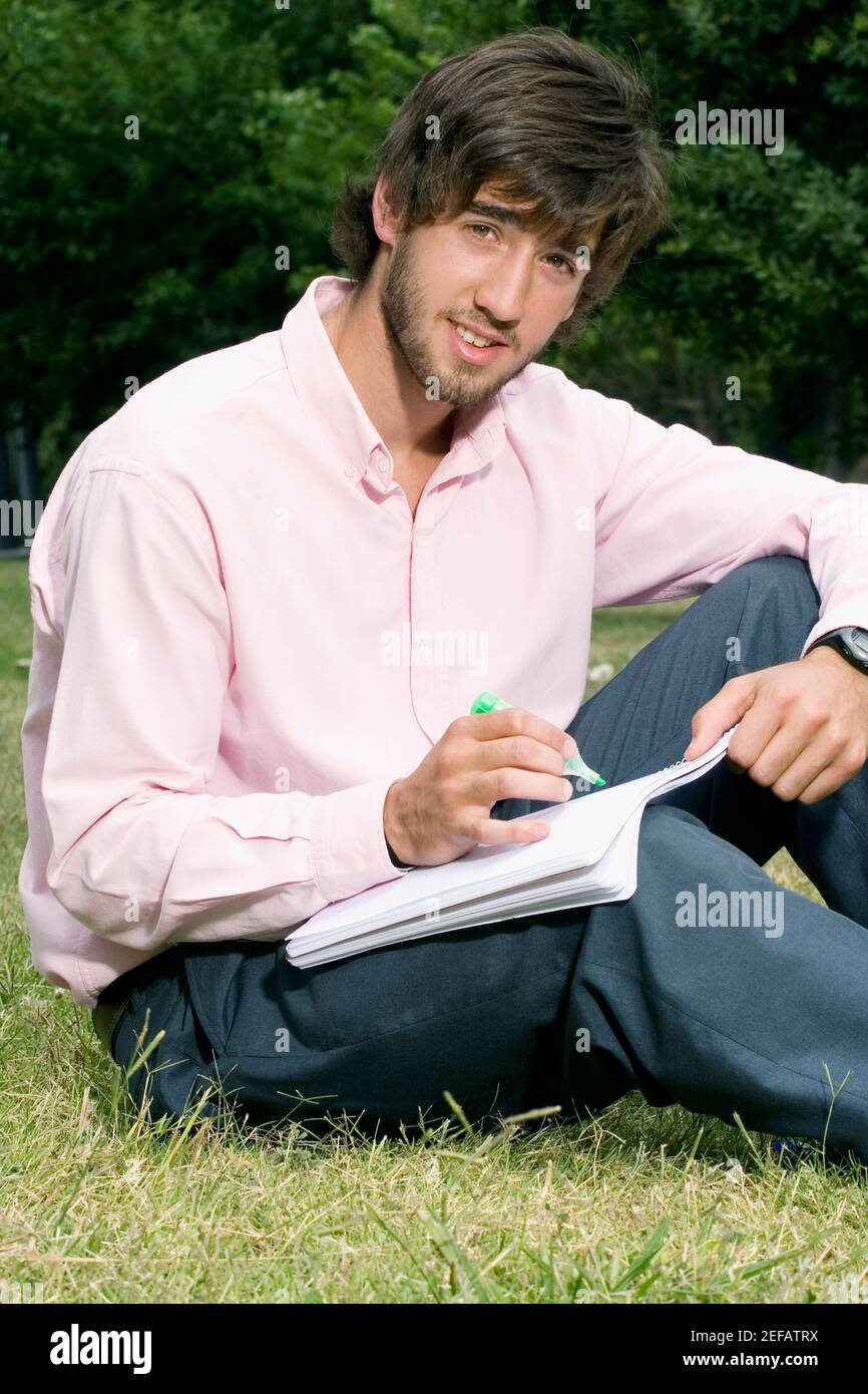 Portrait of a young man writing with a pen on a notepad Stock Photo - Alamy
