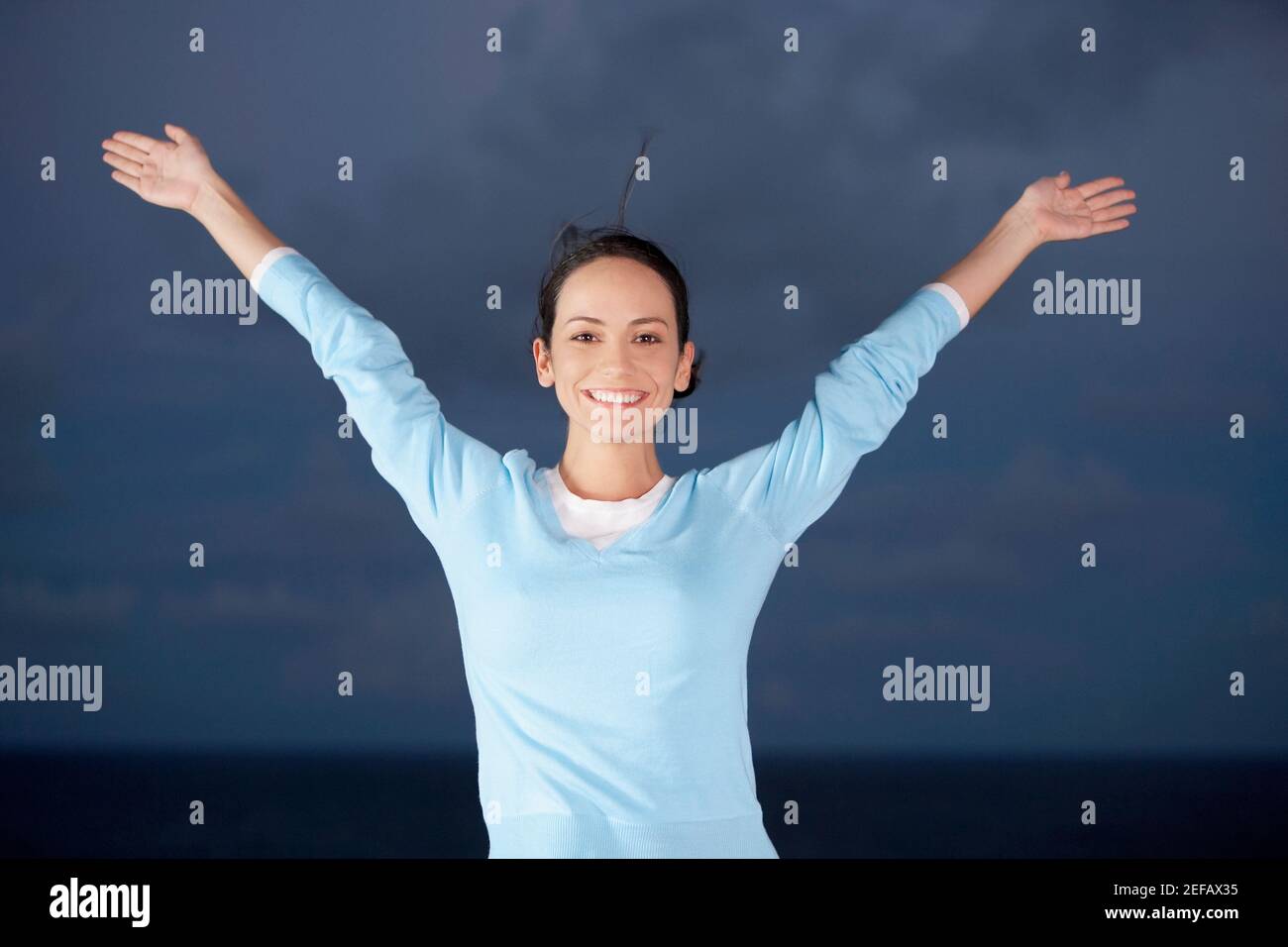Portrait of a young woman smiling with her arms raised Stock Photo - Alamy