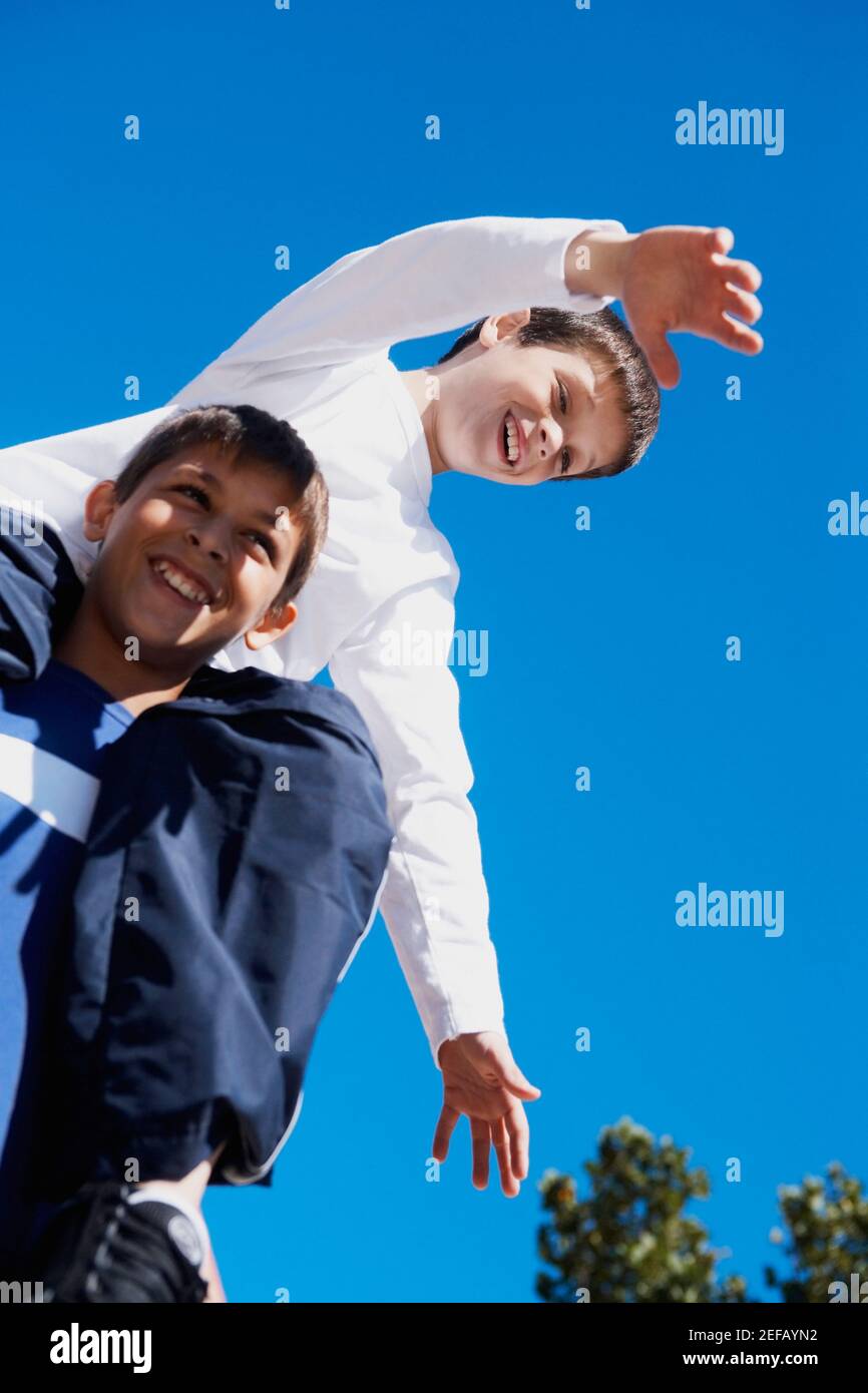 Low angle view of a teenage boy carrying his brother on his shoulders ...