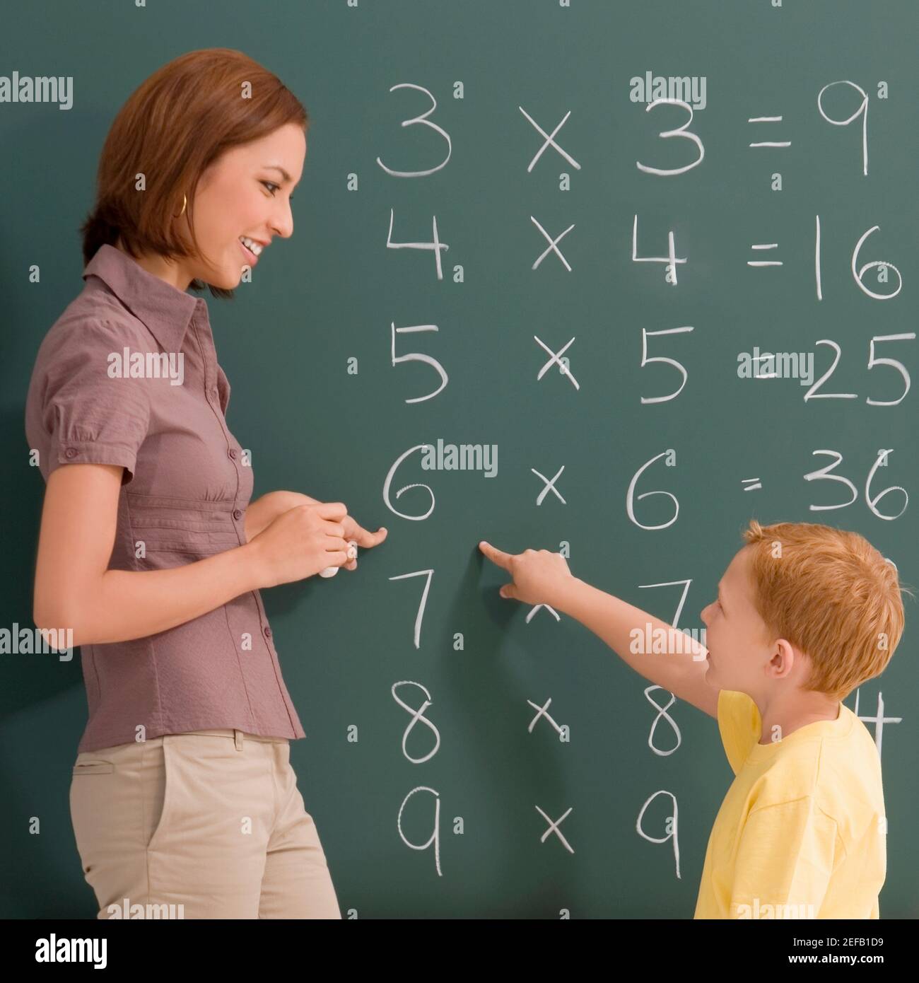 Side profile of a female teacher teaching her student on a blackboard ...